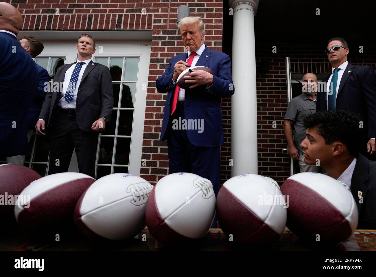 Former President Donald Trump signs a football during a visit to the ...