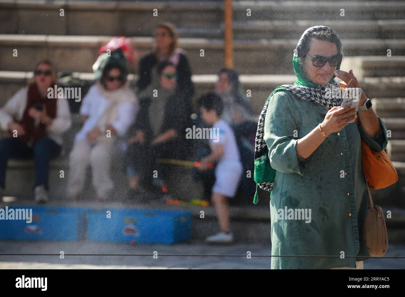 Tehran, Iran. 8th Sep, 2023. A woman uses her mobile phone as her child ...
