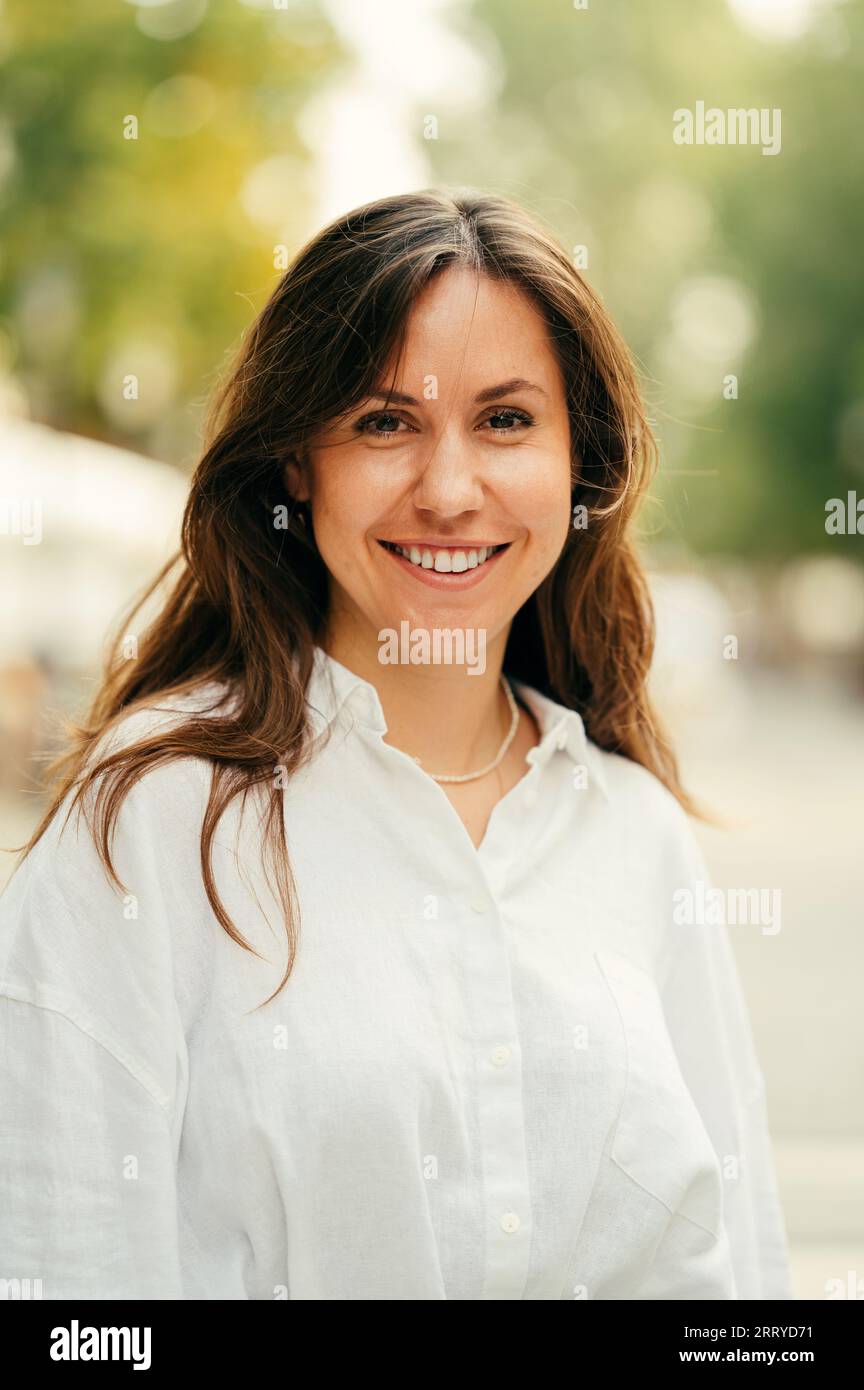 Vertical Street Portrait Of A Young Smiling Woman Wearing White Shirt