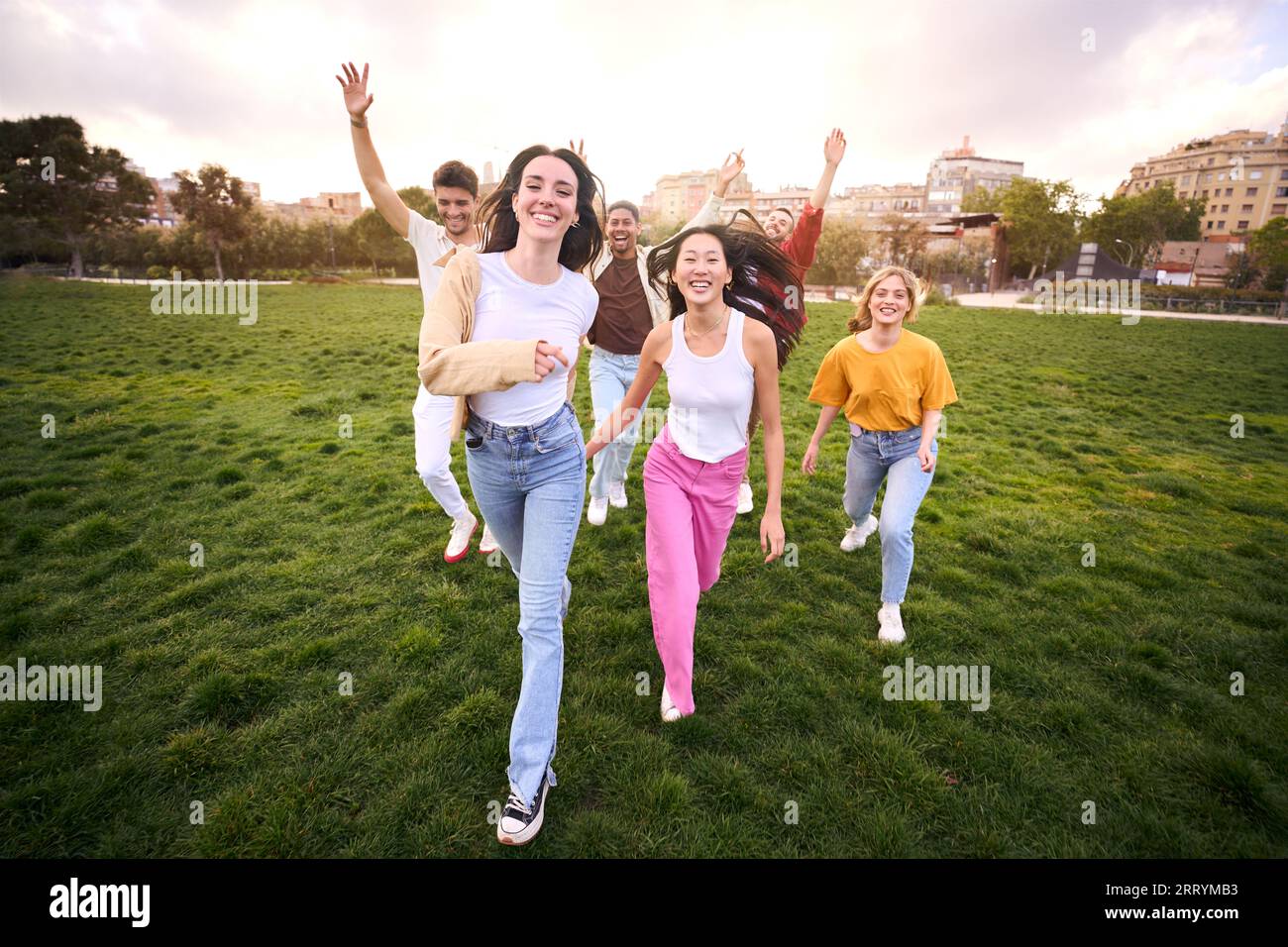 Multiracial youth group having fun and running around green meadow ...