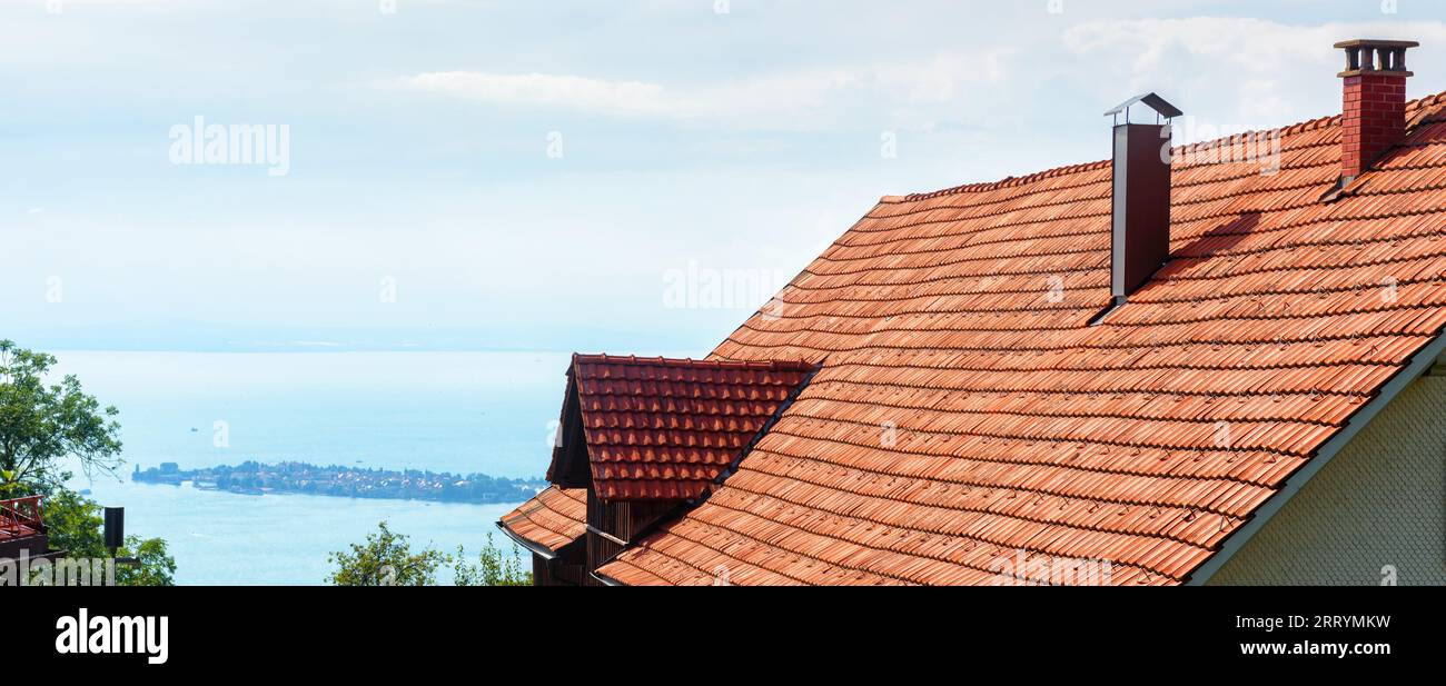 Chimneys on red tiled roof of residential house overlooking lake in ...