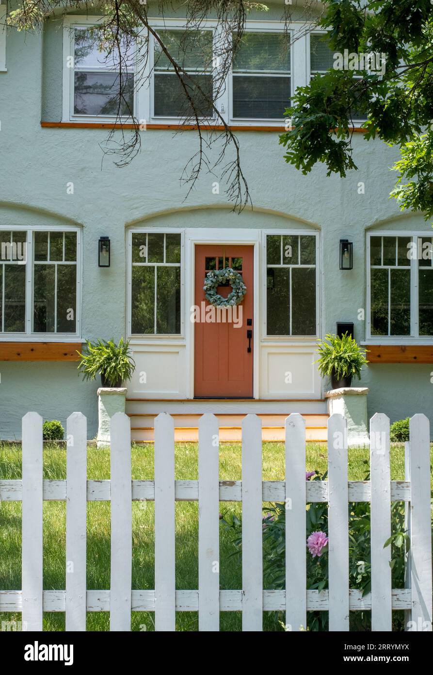 A pretty home has a welcoming entrance and a simple white picket fence ...