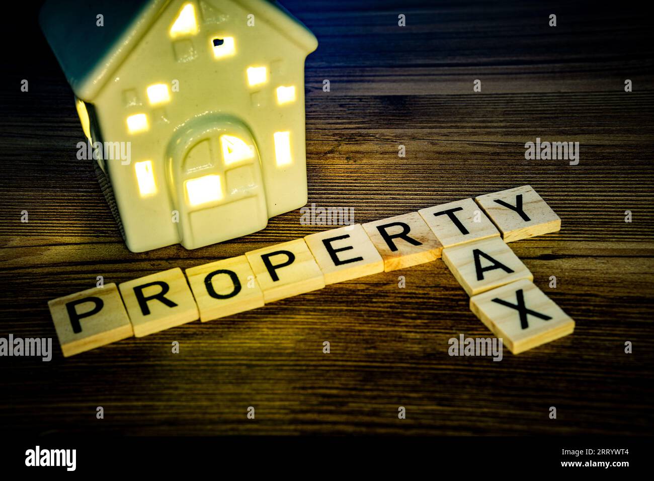 home property tax in wooden letters and a ceramic house with lights on ...