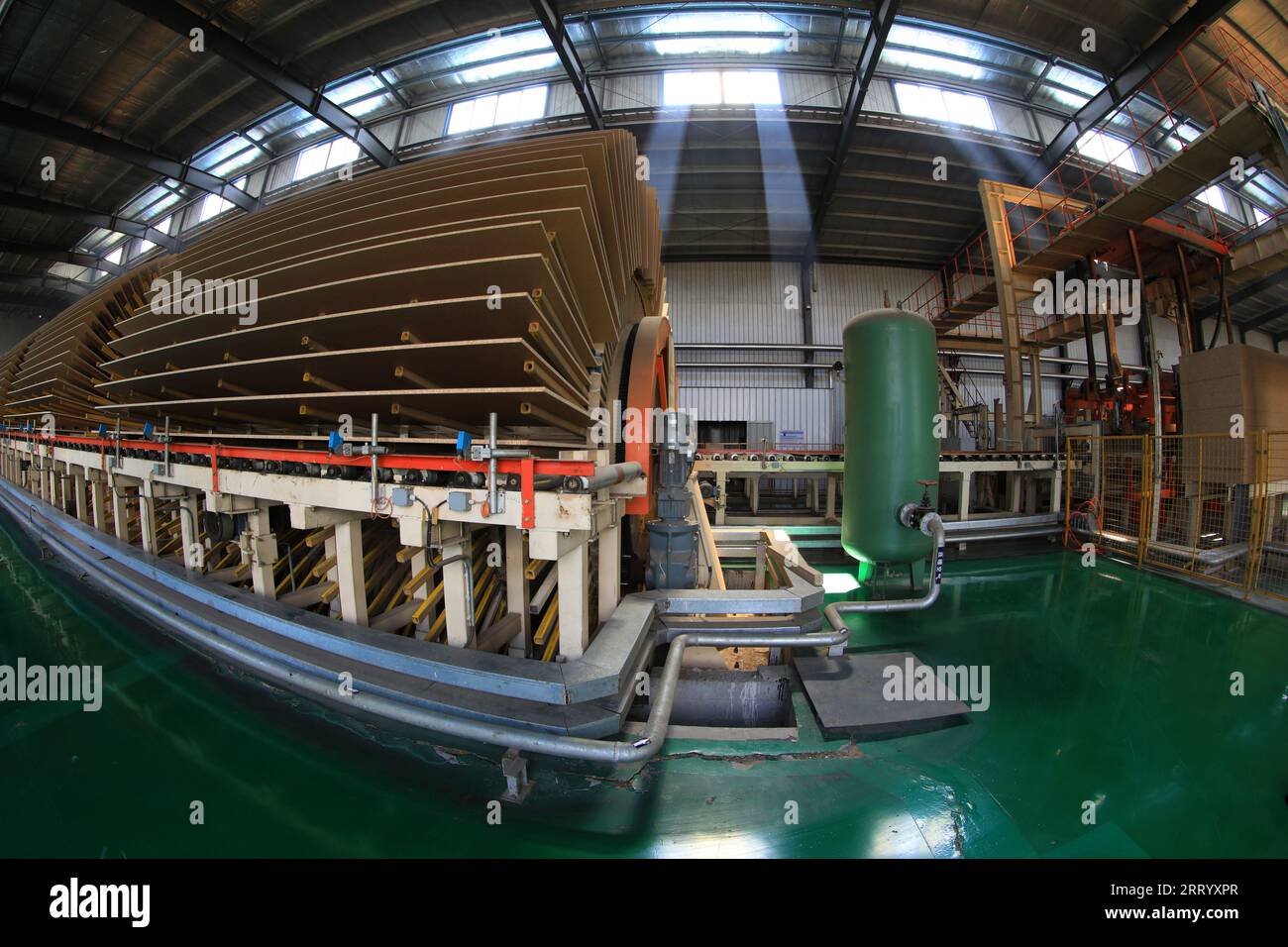 Workers control machinery to produce plates on the production line ...