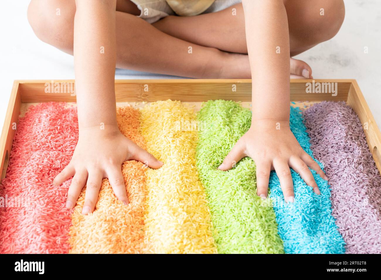 Kids hands in a sensory rice bin Stock Photo - Alamy