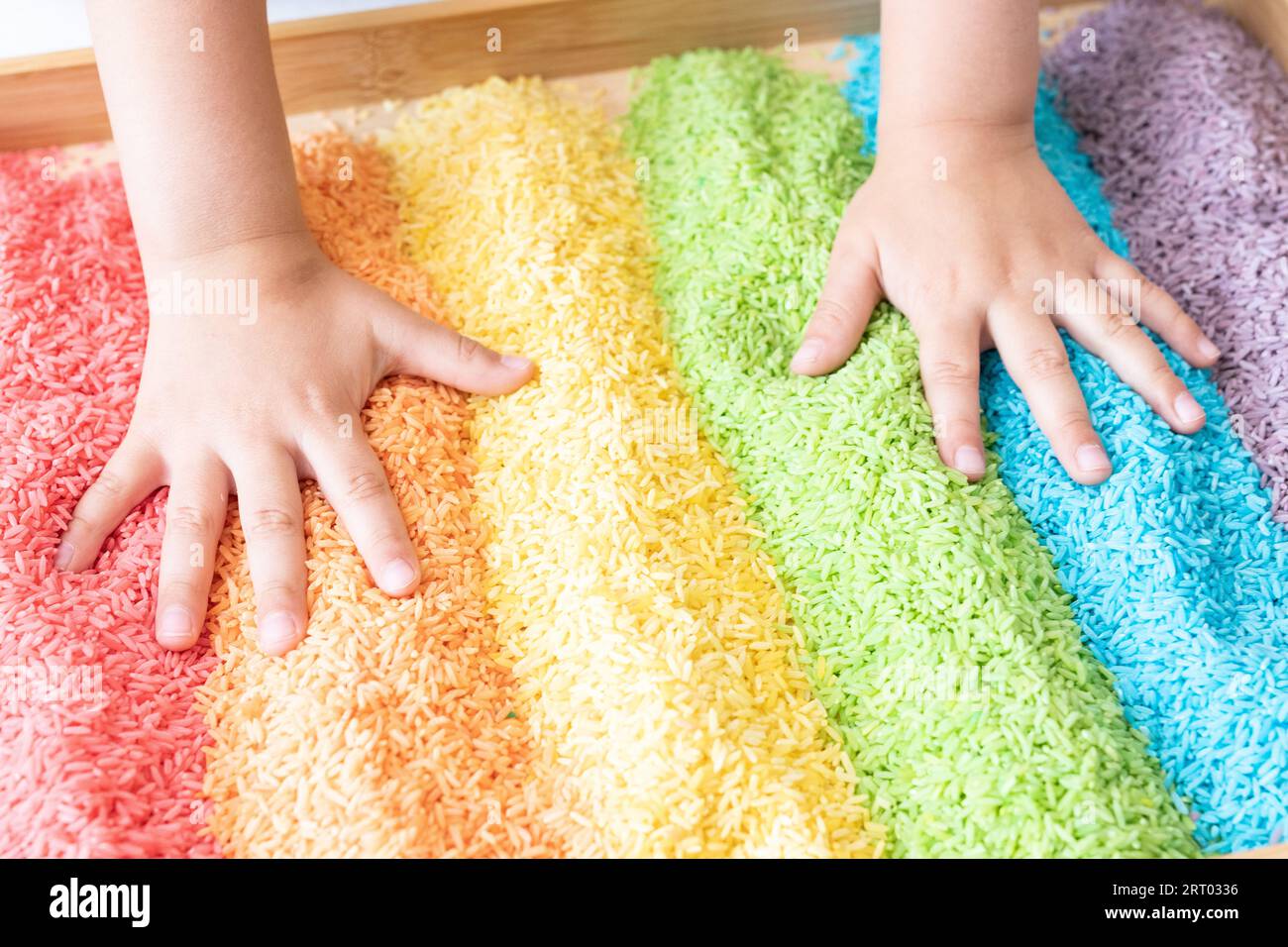 Kids hands in a sensory rice bin Stock Photo - Alamy