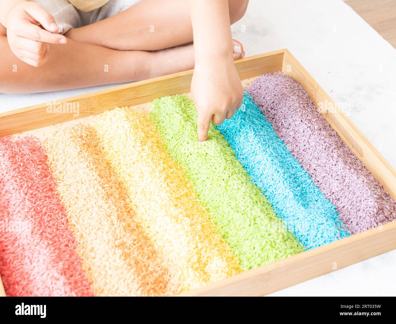 Kids hands in a sensory rice bin Stock Photo - Alamy