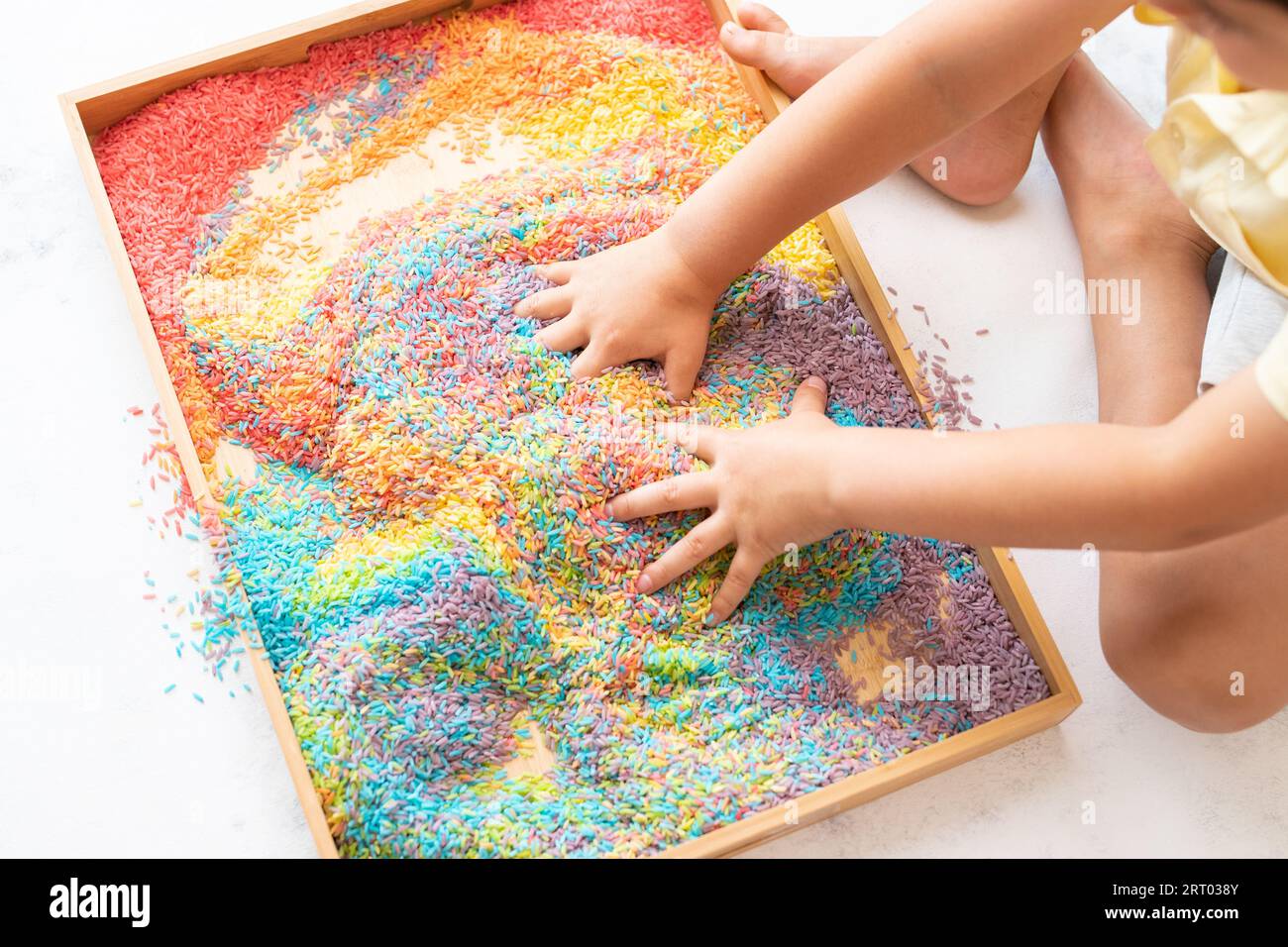 Kids hands in a sensory rice bin Stock Photo - Alamy