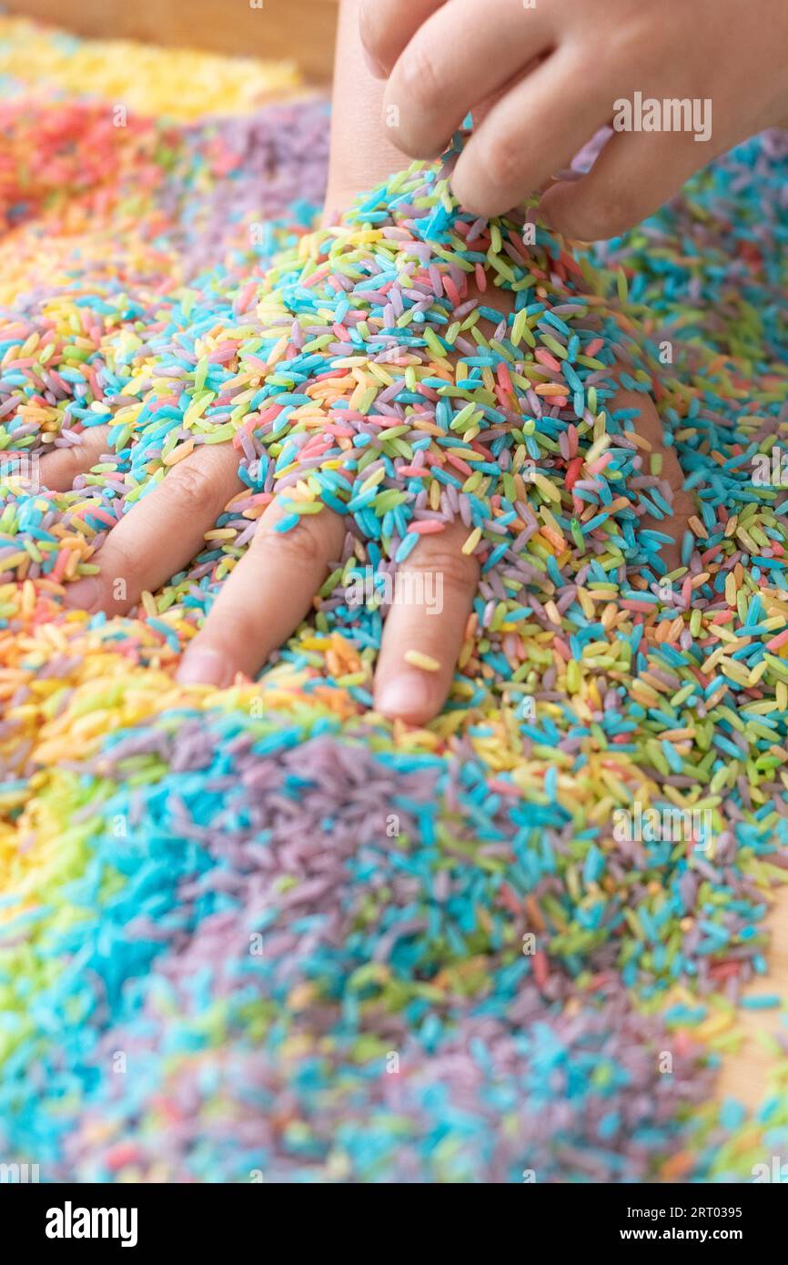 Kids hands in a sensory rice bin Stock Photo - Alamy