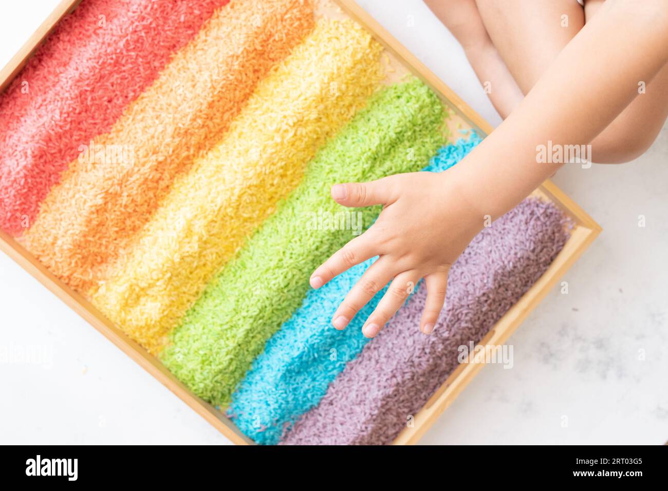 Kids hands in a sensory rice bin Stock Photo - Alamy