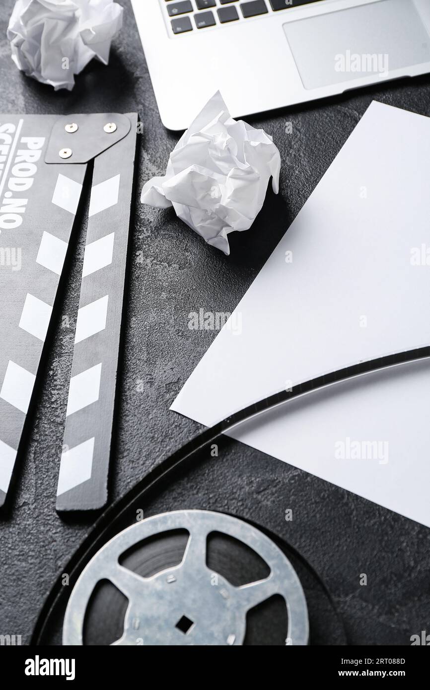Blank paper sheet with movie clapper and film reel on dark background ...