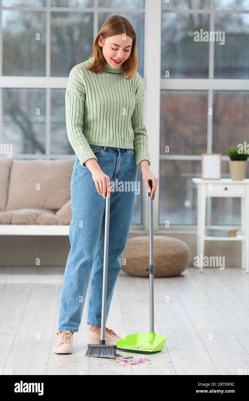 Young woman sweeping floor in room Stock Photo - Alamy