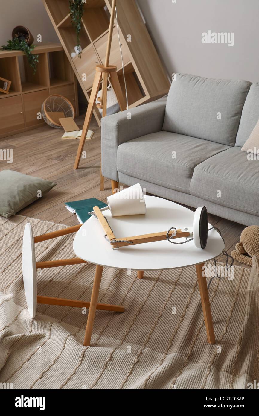Tables with lamp and sofa in messy living room Stock Photo - Alamy