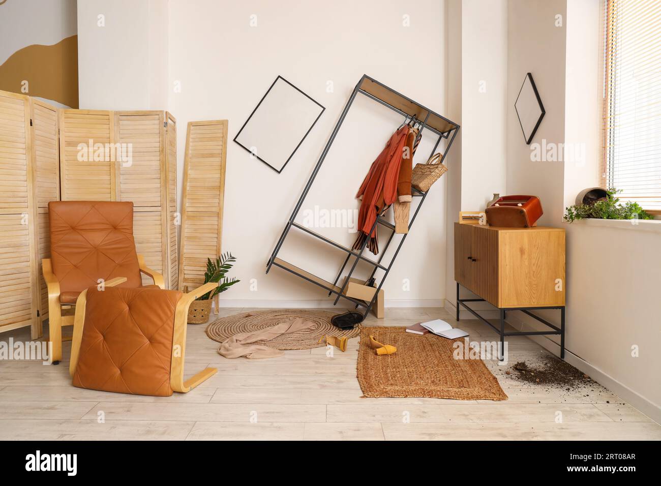 Rack with clothes, drawers and armchair in messy room Stock Photo - Alamy