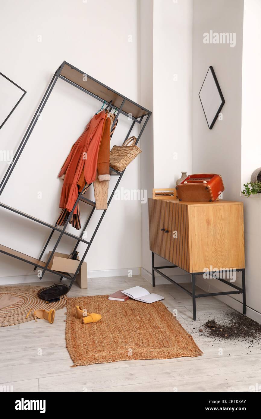 Chest of drawers and rack with clothes in messy room Stock Photo - Alamy