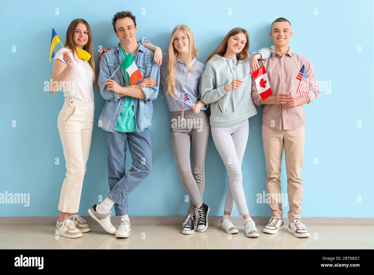 Group of students with flags of different countries near blue wall ...