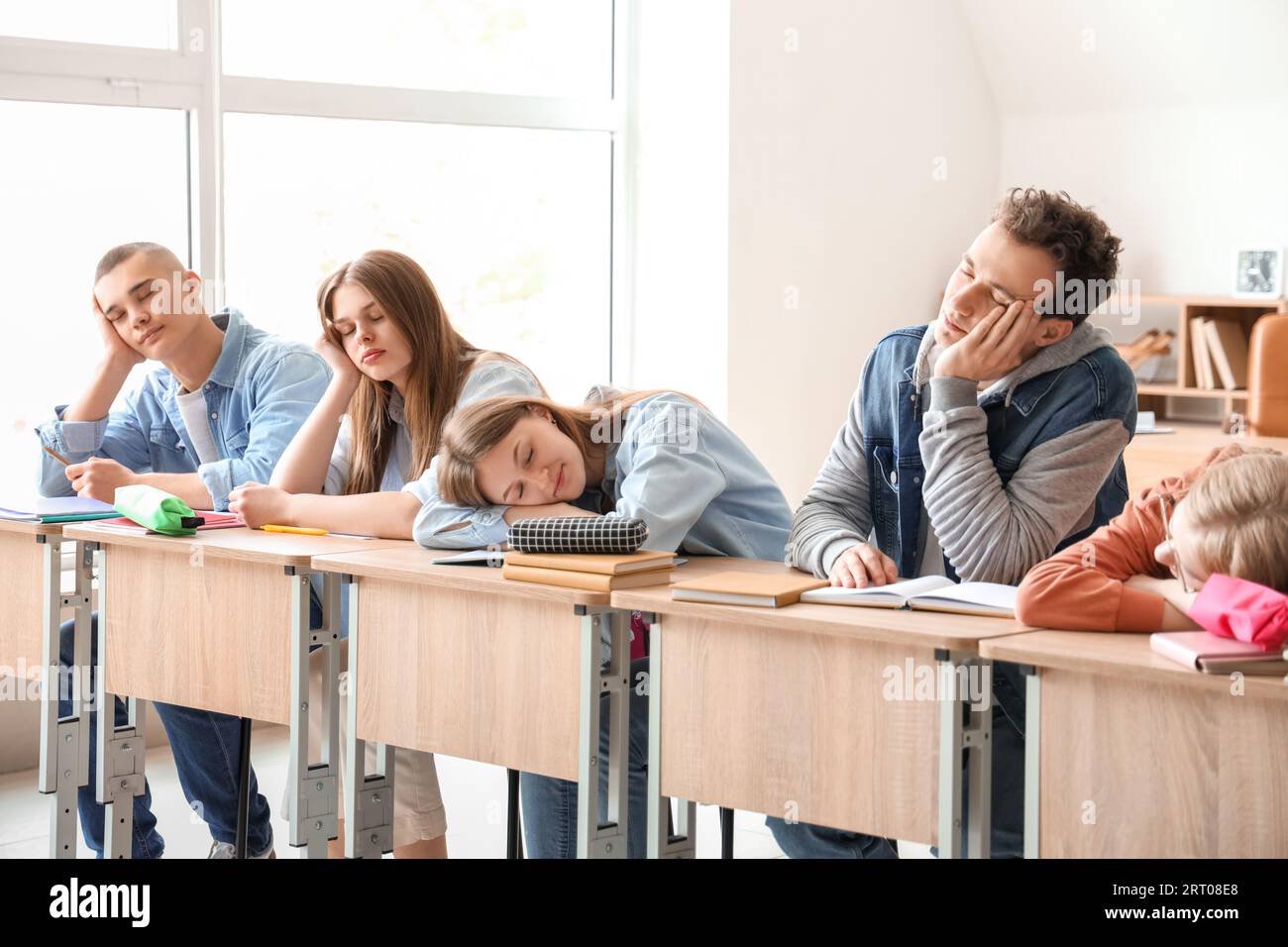Tired sleepy classmates sitting at desks in classroom Stock Photo - Alamy