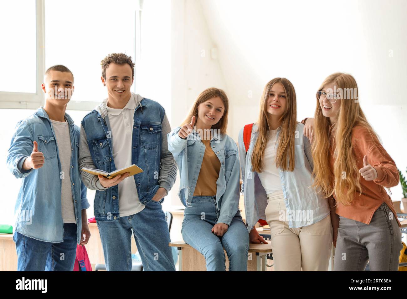 Group of students showing thumb-up gesture in classroom Stock Photo - Alamy