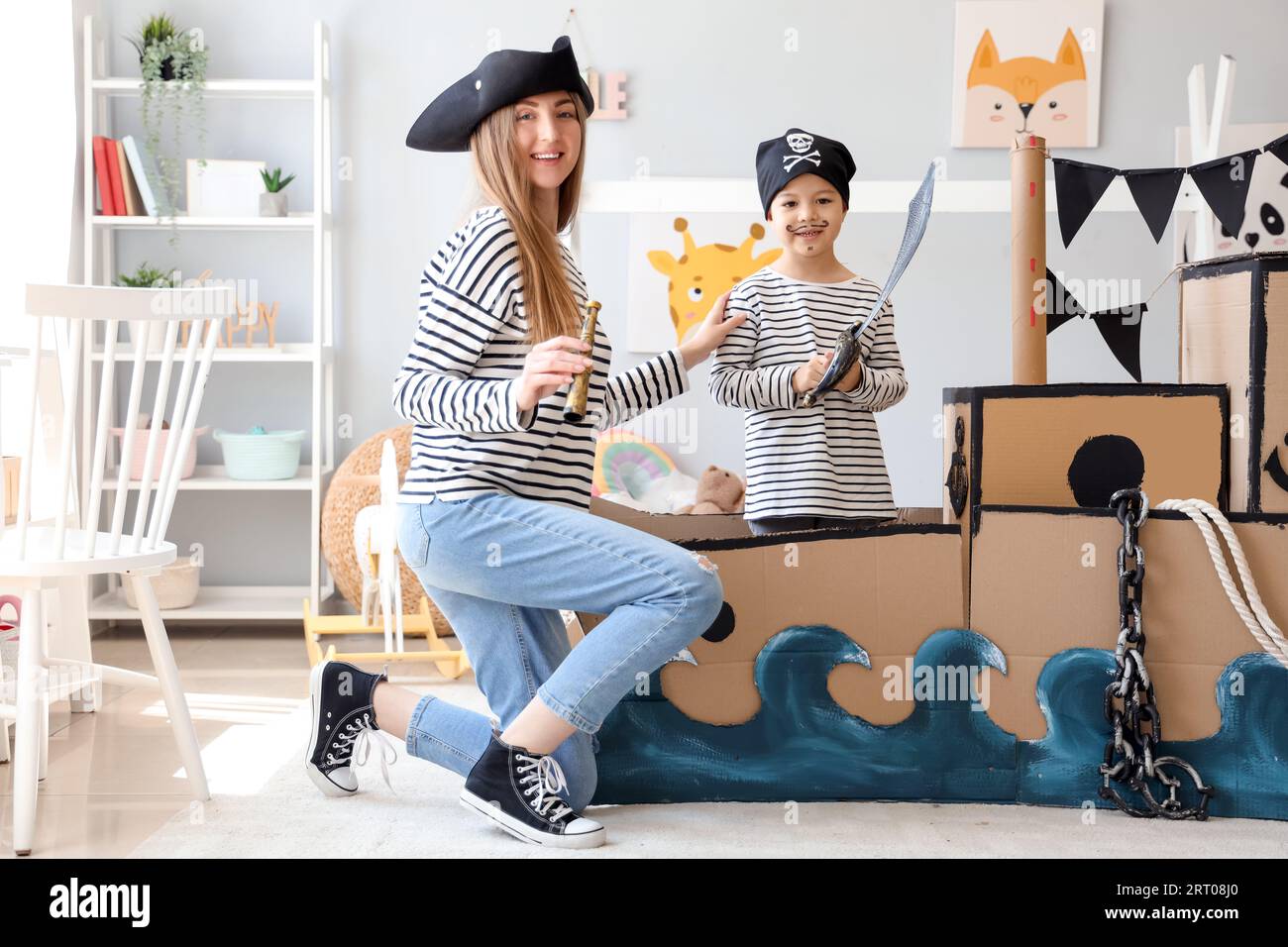 Cute little boy with his mother dressed as pirates playing at home ...