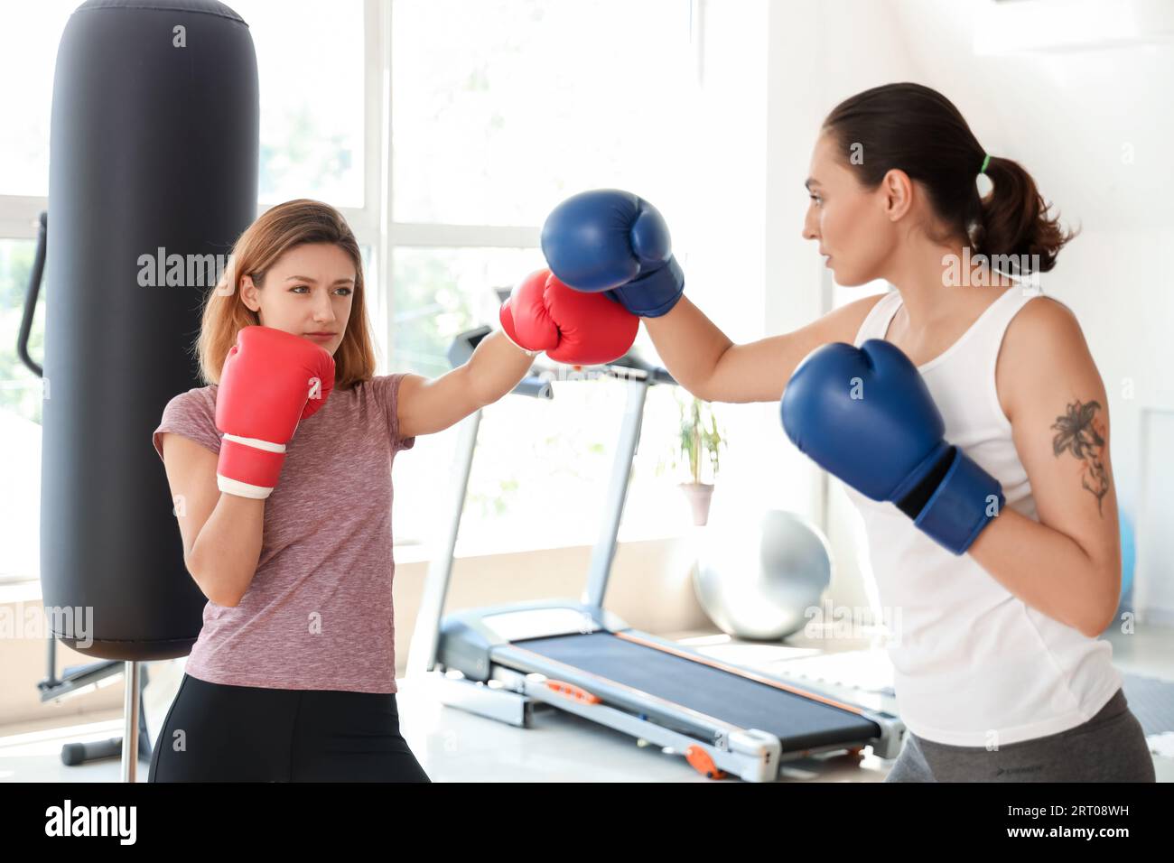 Young women in boxing gloves fighting in gym. Concept of self defense ...
