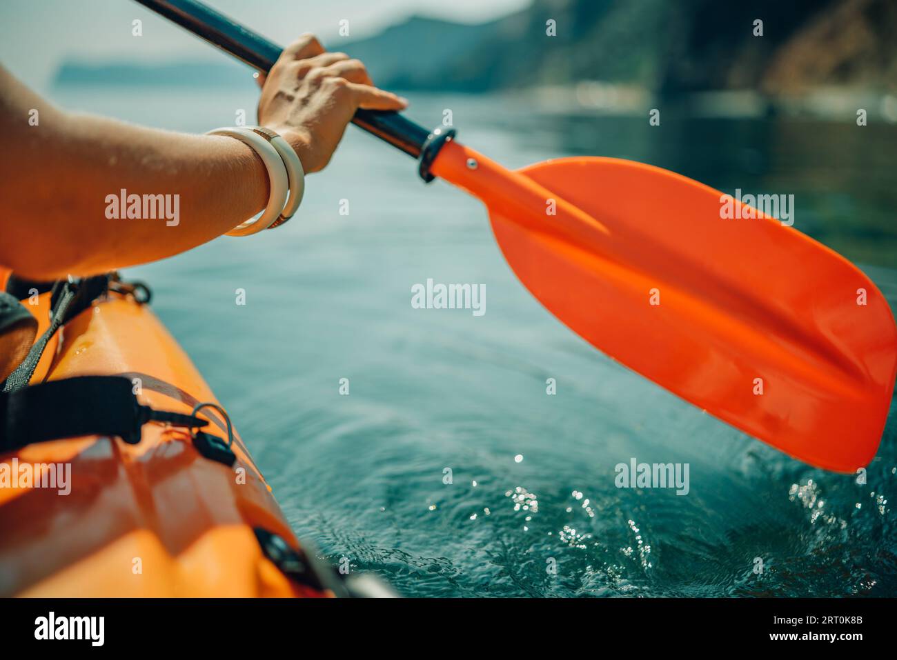 Kayak paddle sea vacation. Person paddles with orange paddle oar on kayak in sea. Leisure active ...
