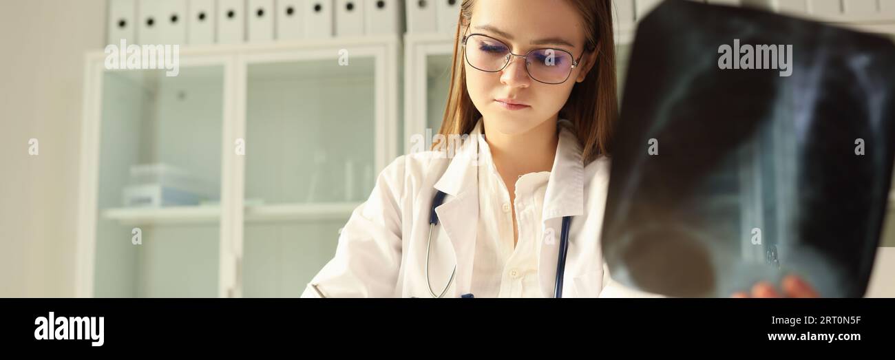 Young doctor in glasses checks x-ray scans and makes notes in medical ...