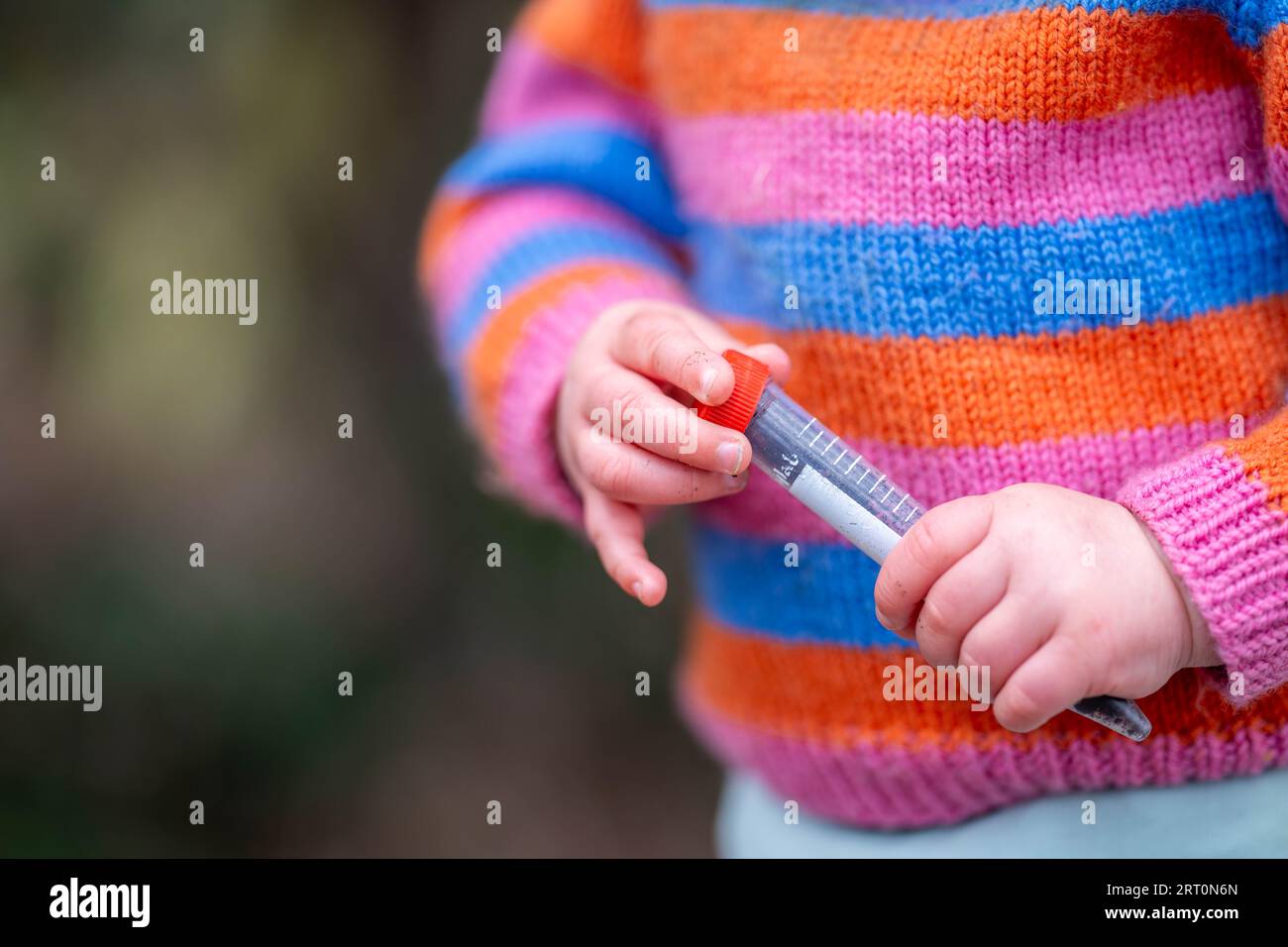 child doing science, toddler with test tubes outside in natural in the ...