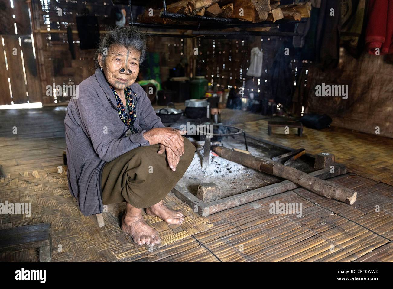 Local woman from Apatani tribe sitting on a small chair in a ...