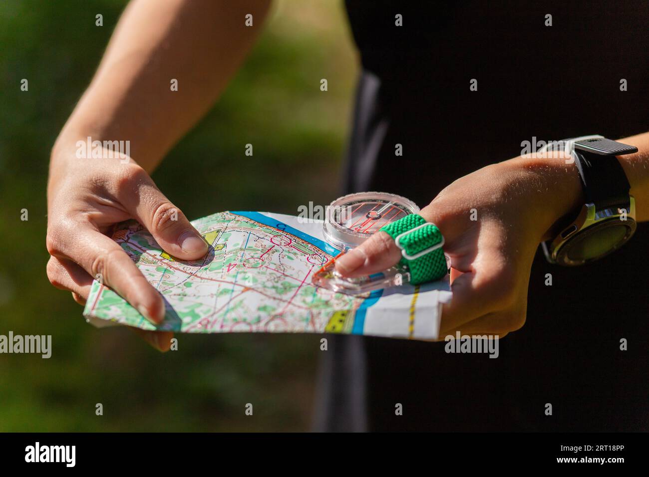 Woman holding a map and the compass during orienteering competitions. Athlete uses navigation ...