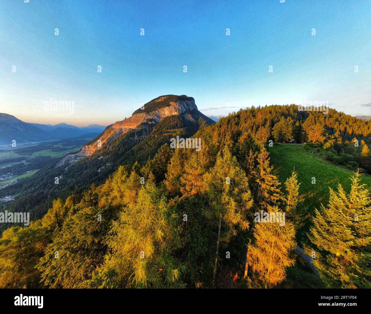 An aerial view of a mountain range covered with green forests at golden ...