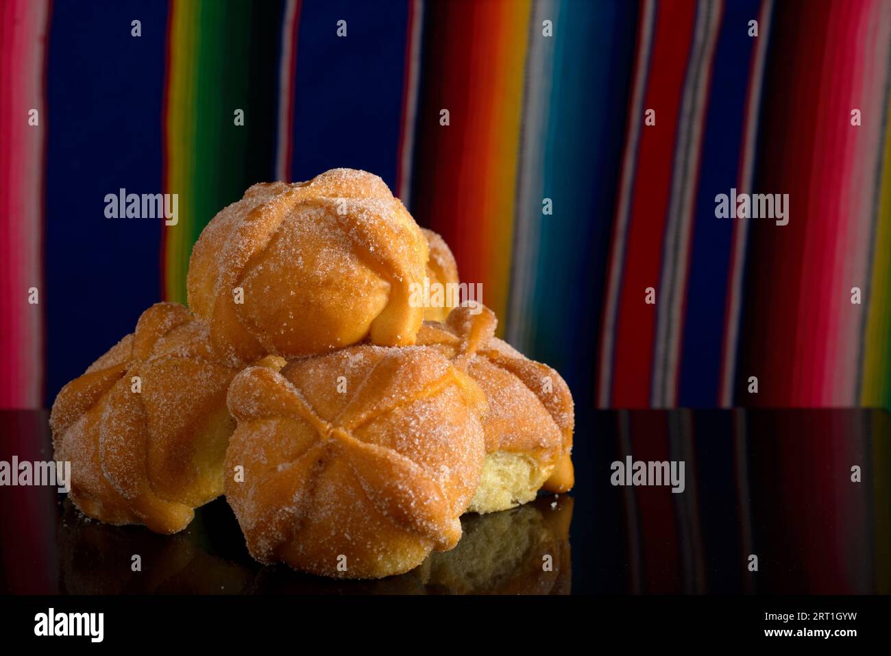 Dead bread on black glass table with colorful serape in the background ...