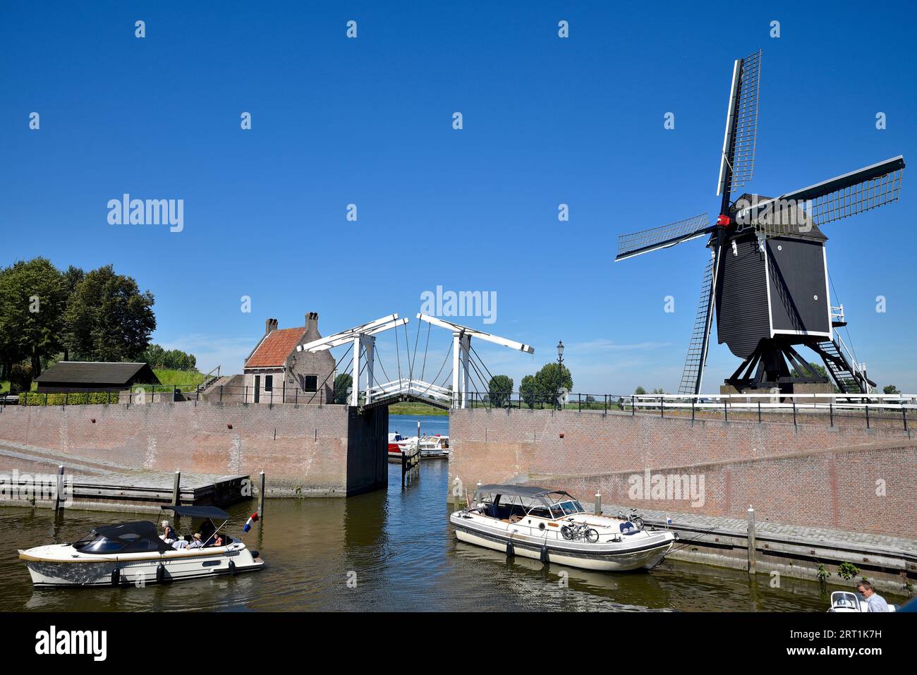 Harbor of Heusden with quay wall, white drawbridge, boats and mill ...