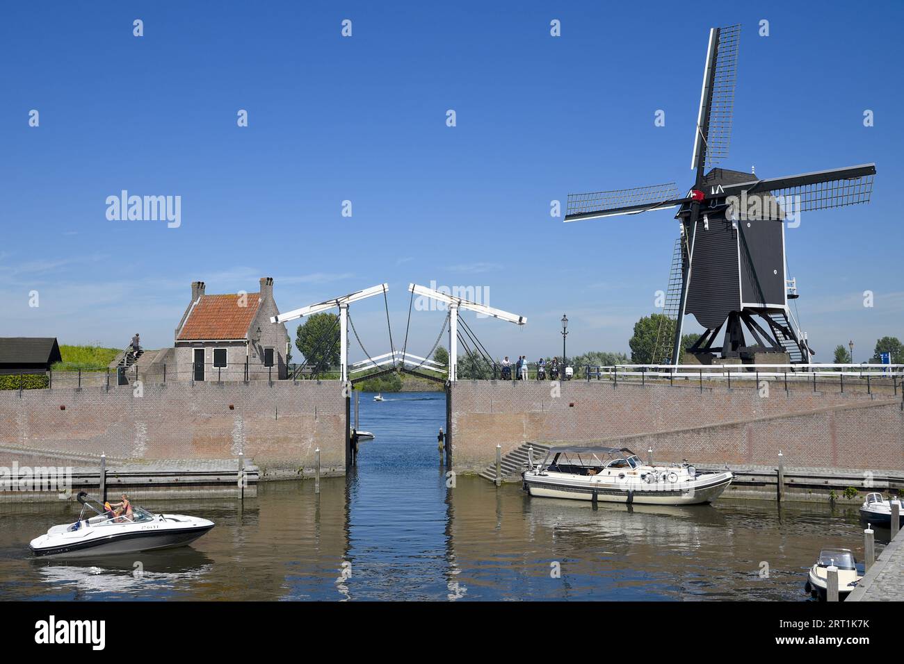Harbor of Heusden with quay wall, white drawbridge, boats and mill ...