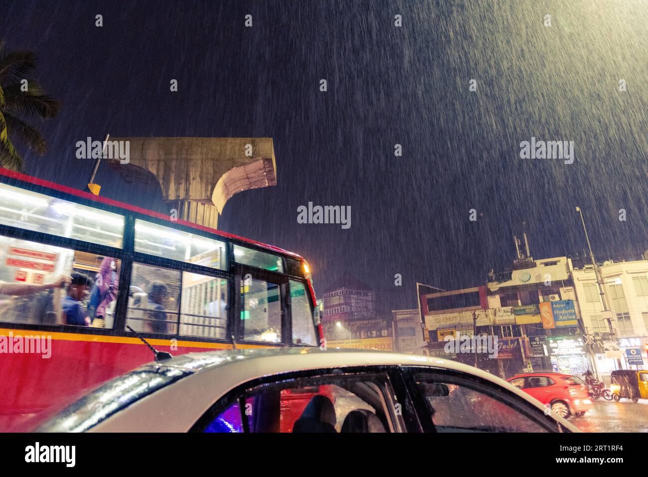 Street scene with public transport in heavy rainfall at night during ...