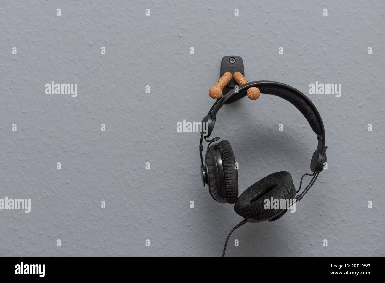 Studio headphones hanging on gray wall Stock Photo - Alamy