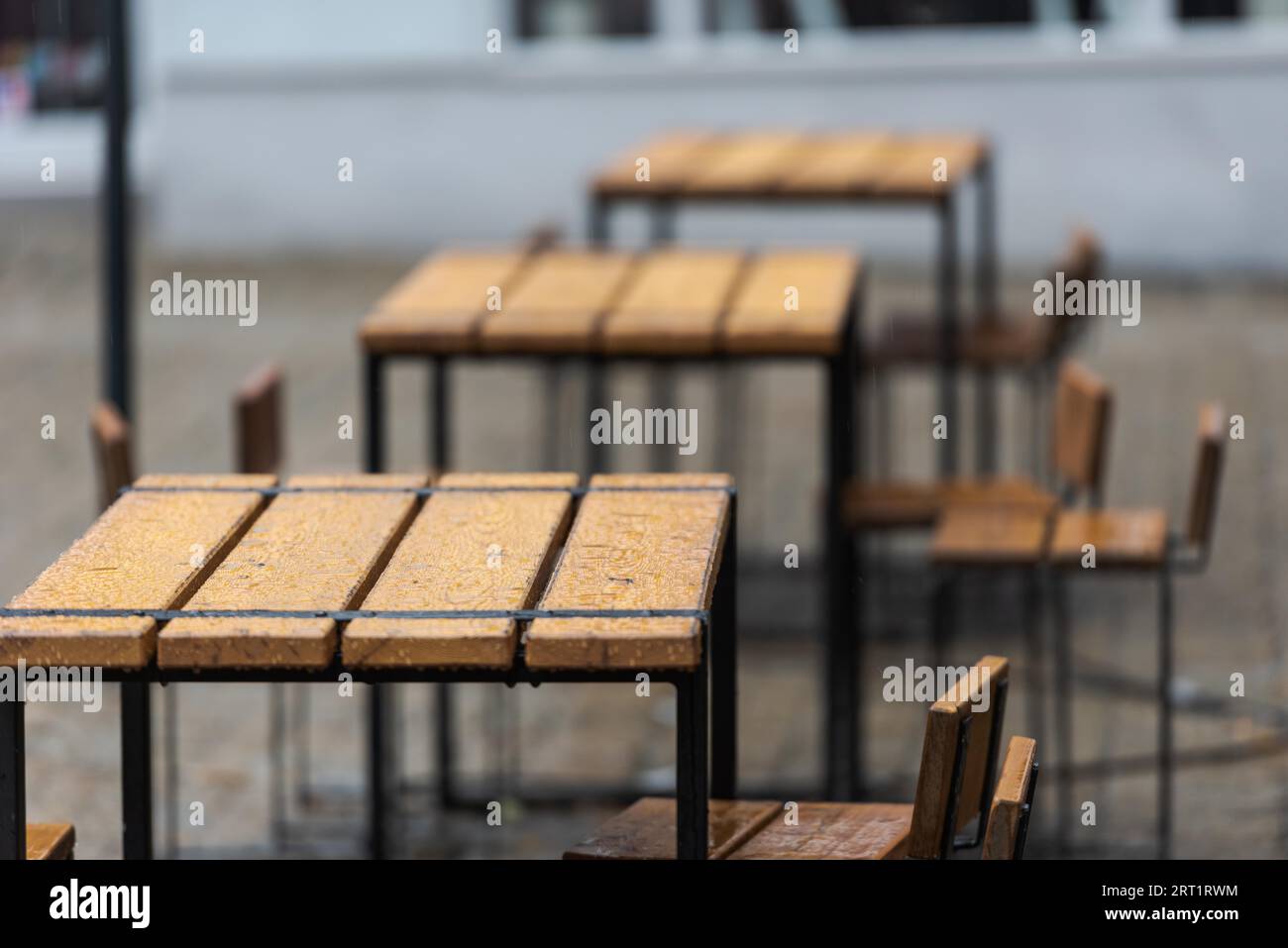 Empty and wet vintage wooden tables and chairs of closed outdoor ...