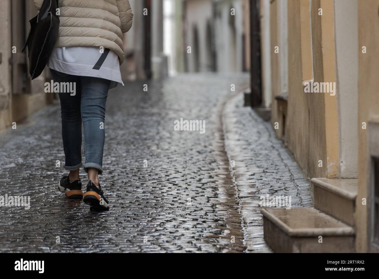 Lower body part of unrecognizable woman walking through rainy street in ...