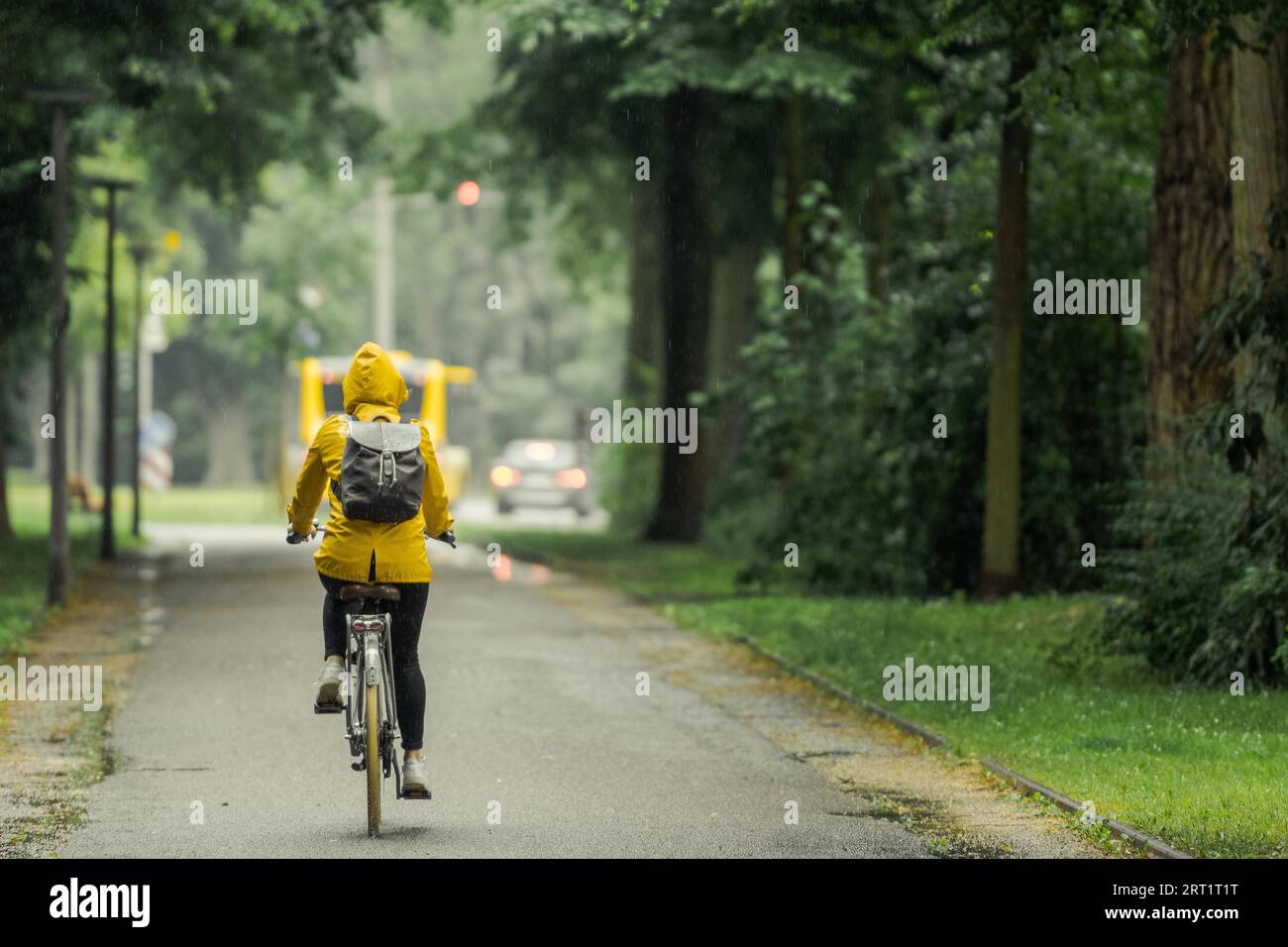 One unrecognizable person with yellow oilskin on bike riding through ...
