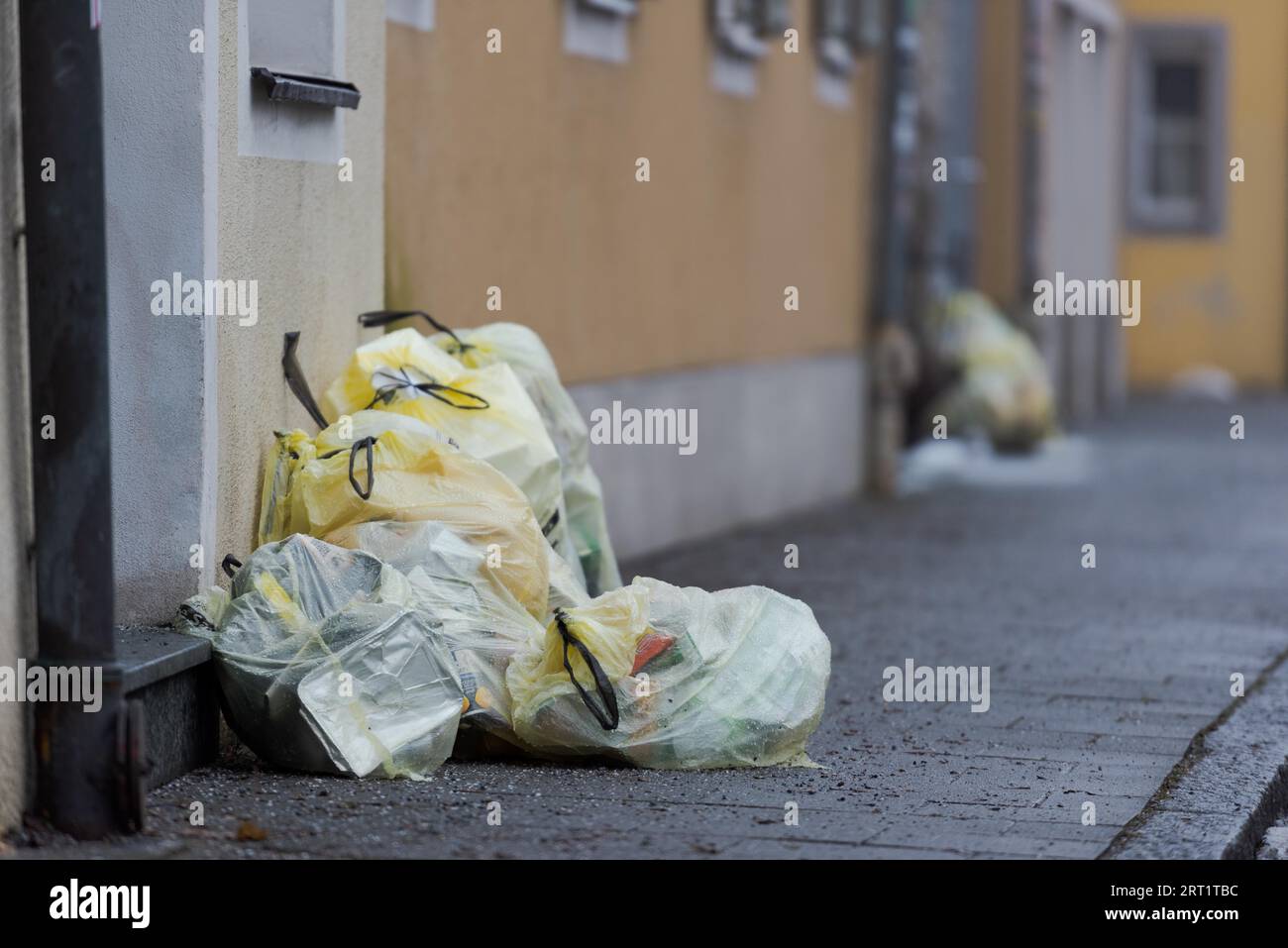 Yellow plastic sacks containing plastic garbage piled up near front ...