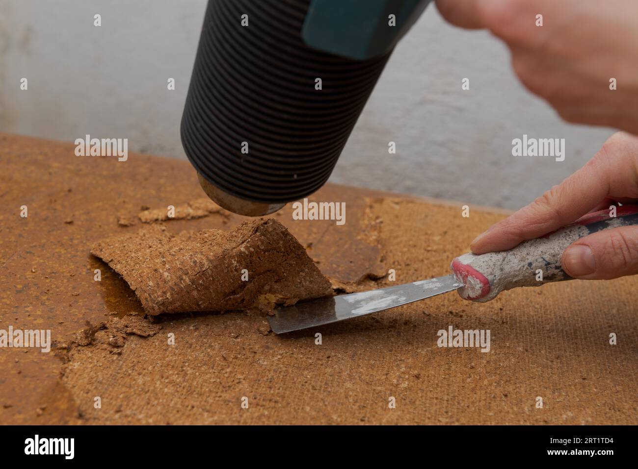 Human hand with scraper and hot air blower scraping off old surface of ...
