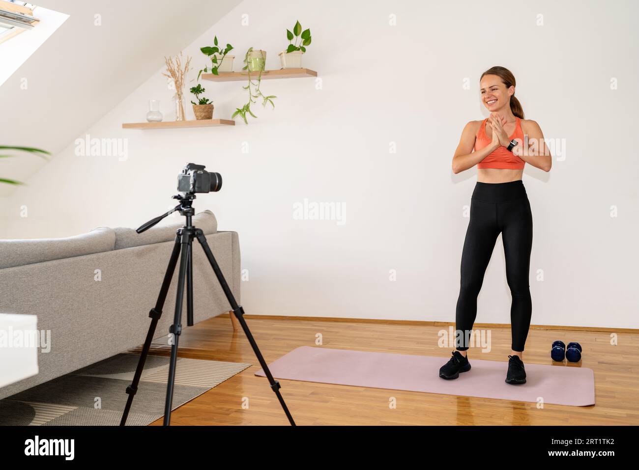 Woman fitness coach vlogger standing at home in front of video camera ...