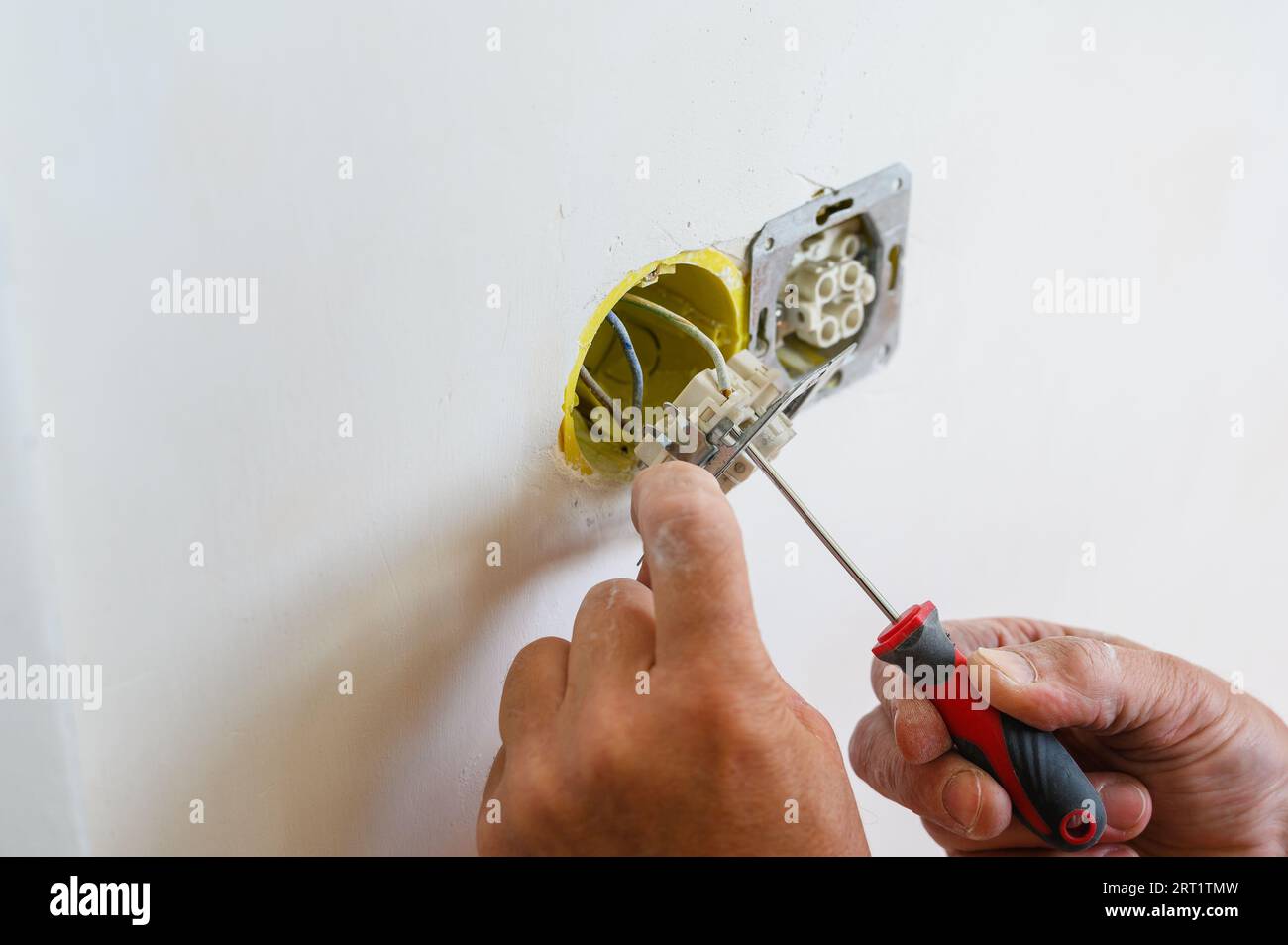 An electrician installs a socket in the wall. Close-up Stock Photo - Alamy