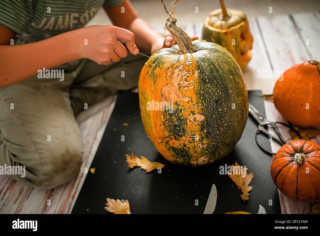 boy's hands are a blur of activity as he carves a ghoulish grin on the ...