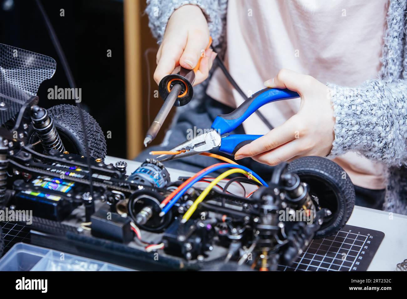 A young girl learns how to solder and is attaching an ESC to a motor in ...