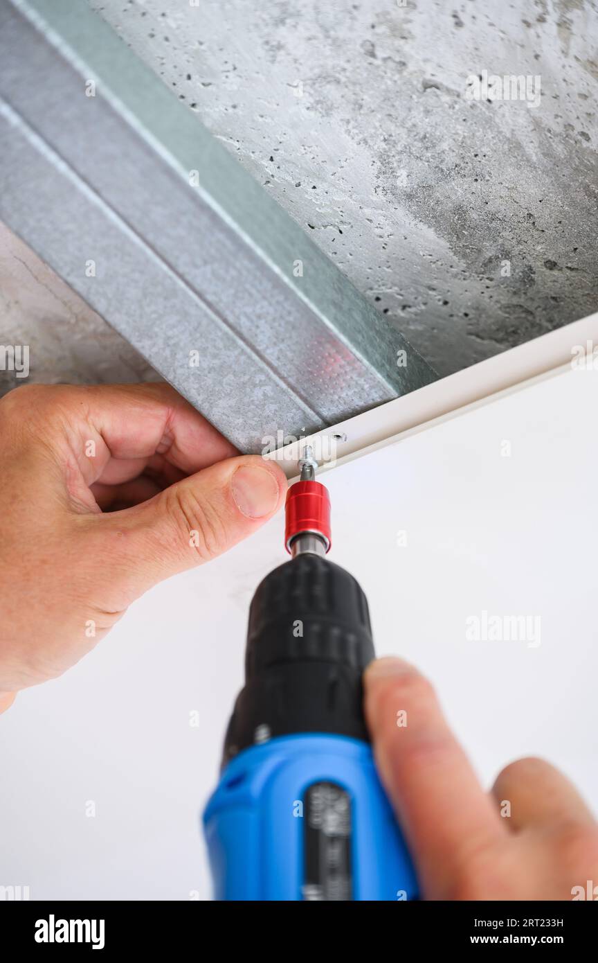 Construction worker assemble a suspended ceiling and fixing the plastic ...