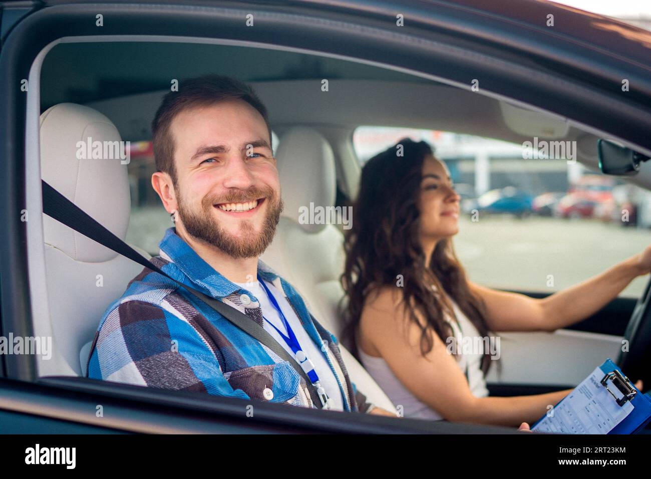 Happy male instructor with checklist sitting on the passenger seat ...