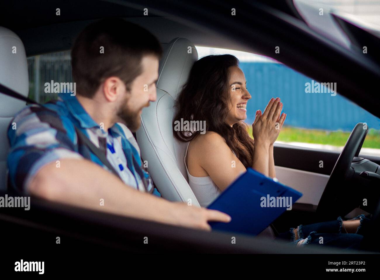 Happy young lady getting a driving lesson in a car, smiling instructor ...