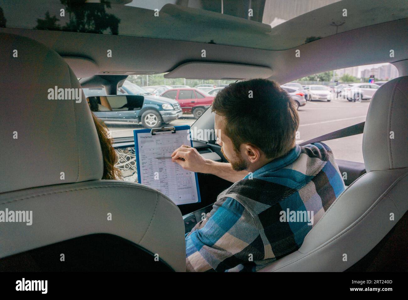 Back view of male instructor sitting on the passenger seat while ...