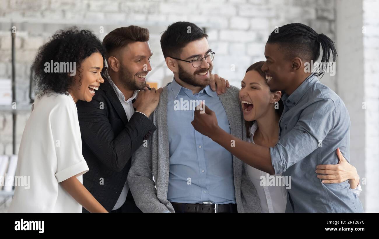 Overjoyed diverse colleagues hug show team unity Stock Photo - Alamy