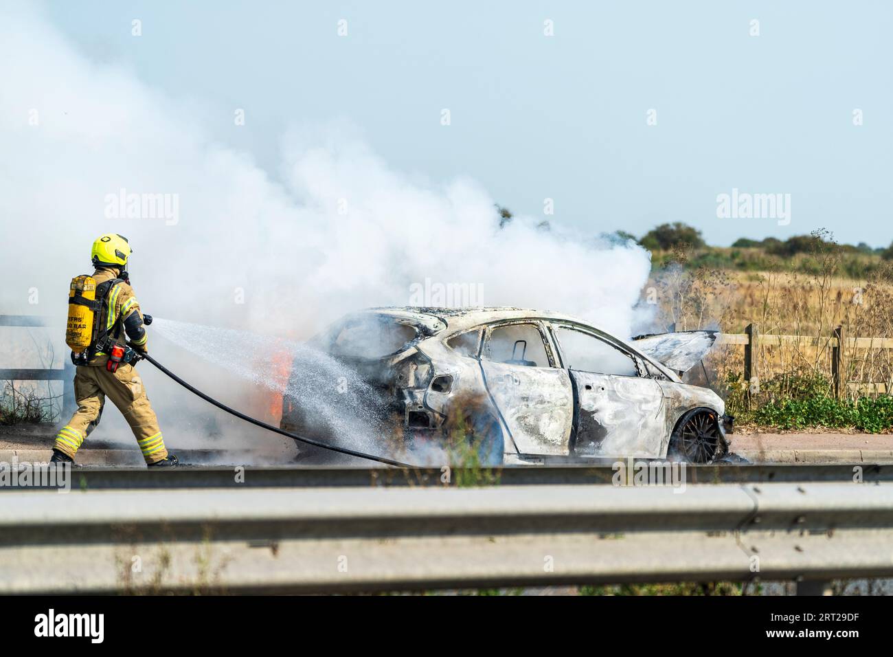 Fireman attending a car fire on a layby on a major road, A299 in the ...